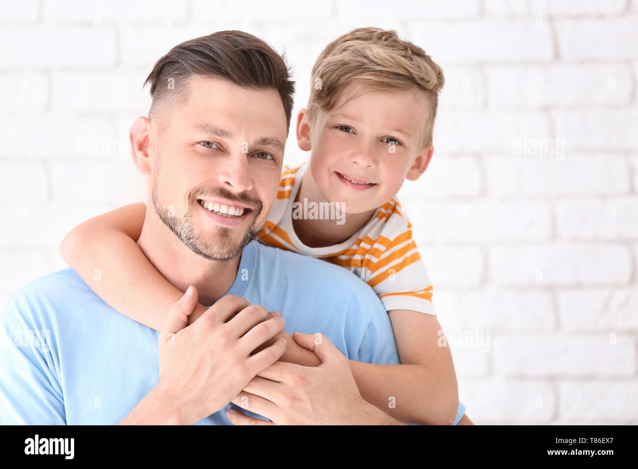 Little boy and his dad on light background Stock Photo - Alamy