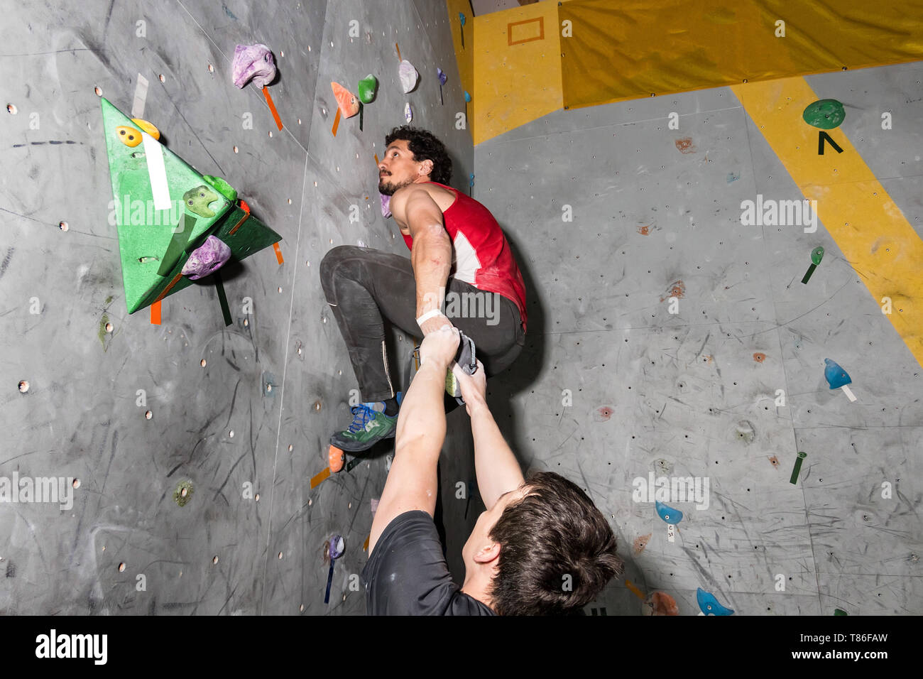 Rock climber man hanging on a bouldering climbing wall, inside on ...