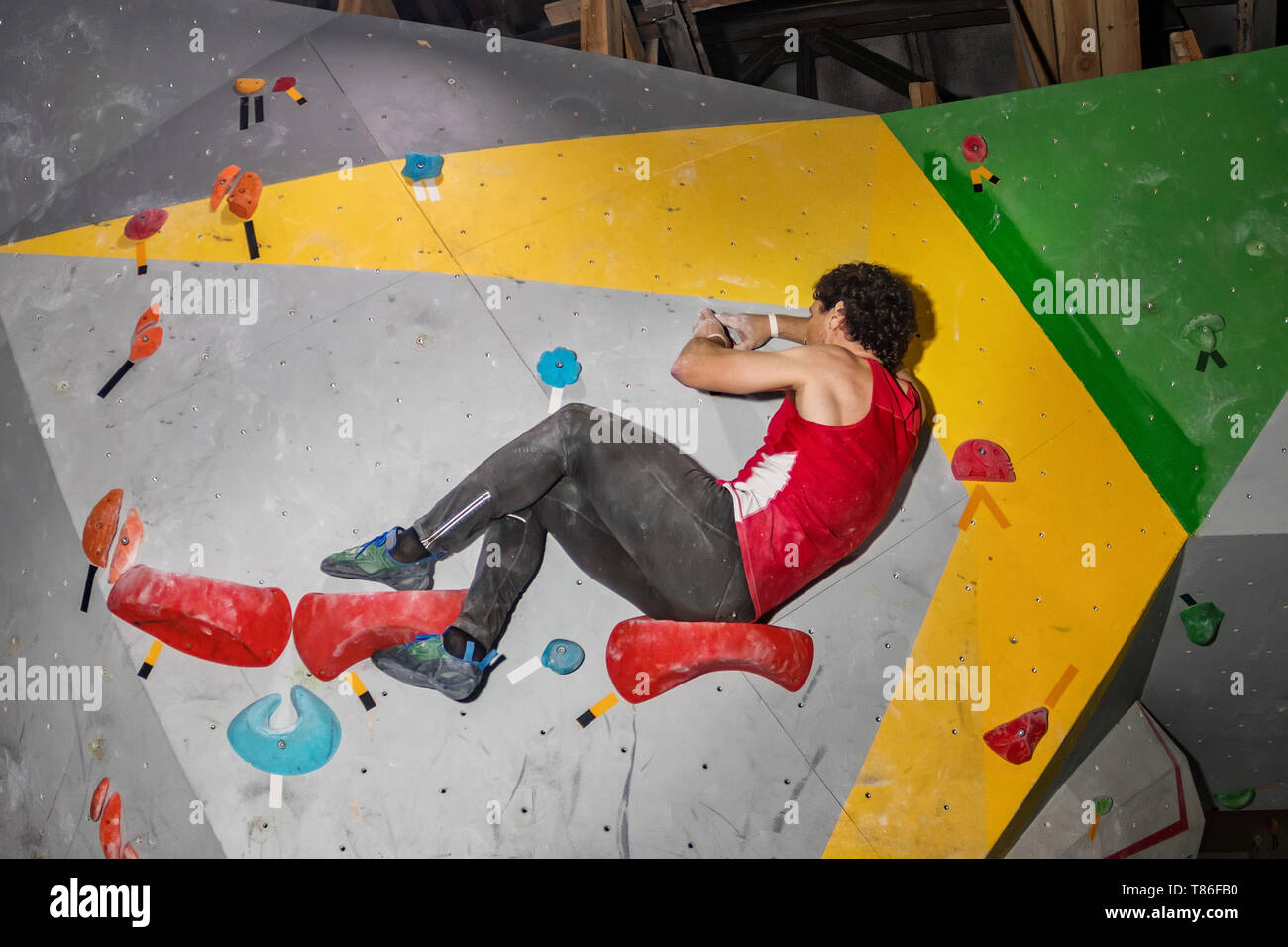 Rock climber man hanging on a bouldering climbing wall, inside on ...