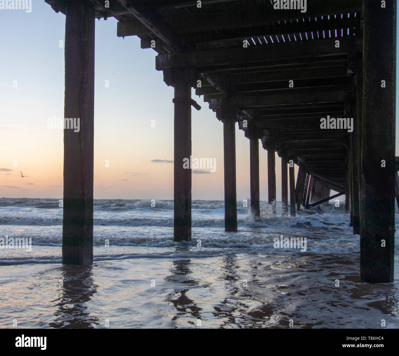 Sunrise at Claremont Pier with waves breaking over the super-structure ...