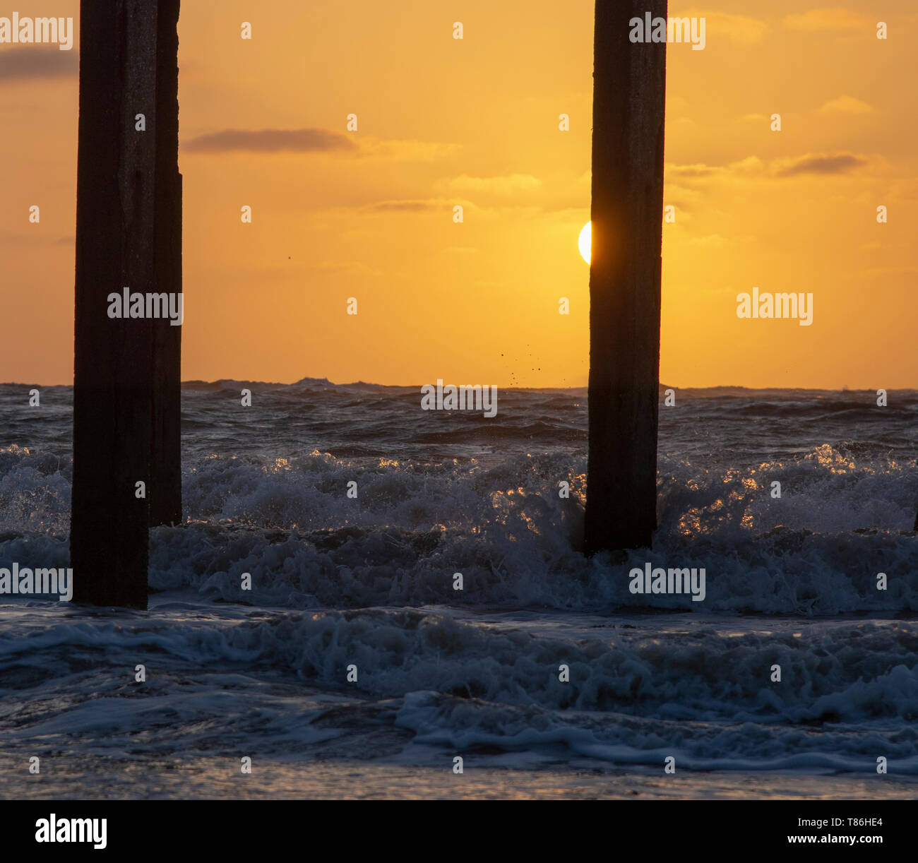 Sunrise at Claremont Pier with waves breaking over the super-structure ...