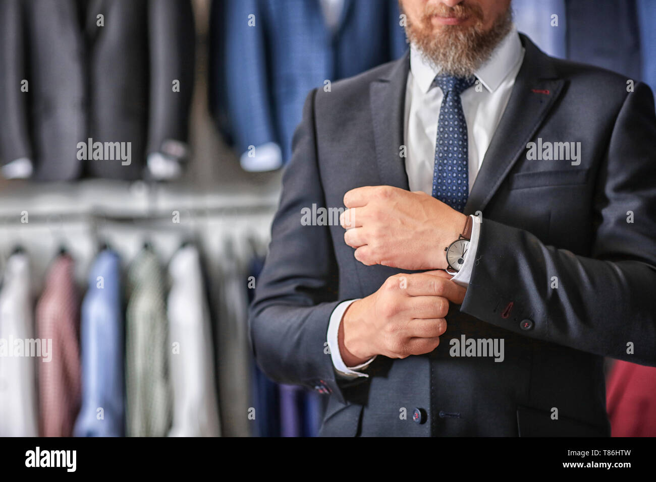 Mature businessman in suit with wristwatch in menswear store Stock ...