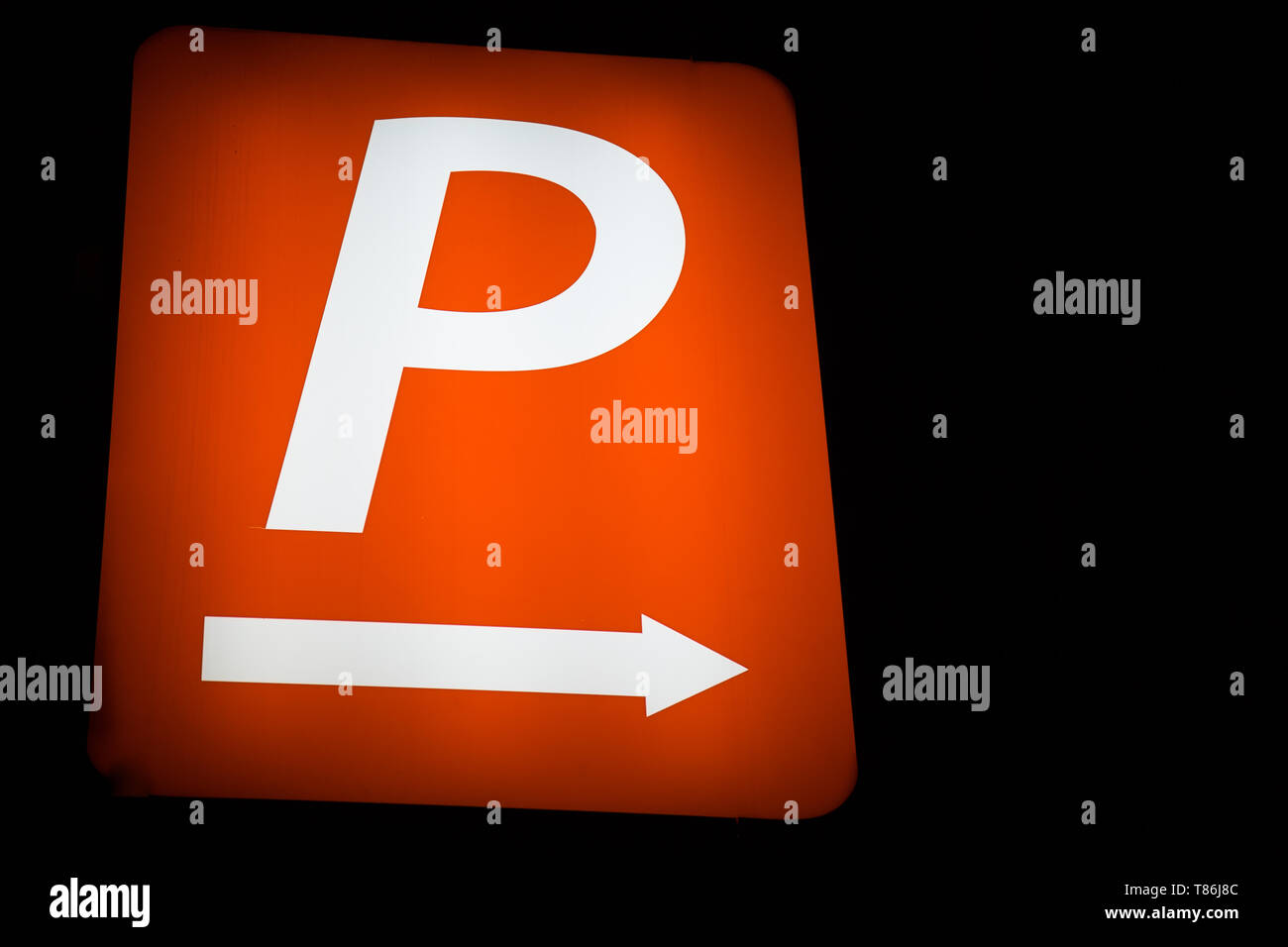 Orange parking sign indicator arrow dark background closeup copy space ...