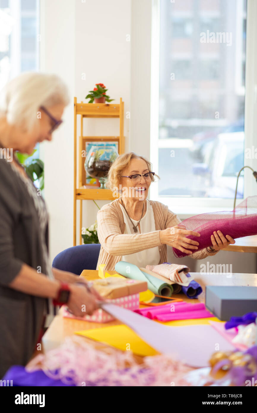 Nice joyful woman passing the wrapping paper Stock Photo - Alamy