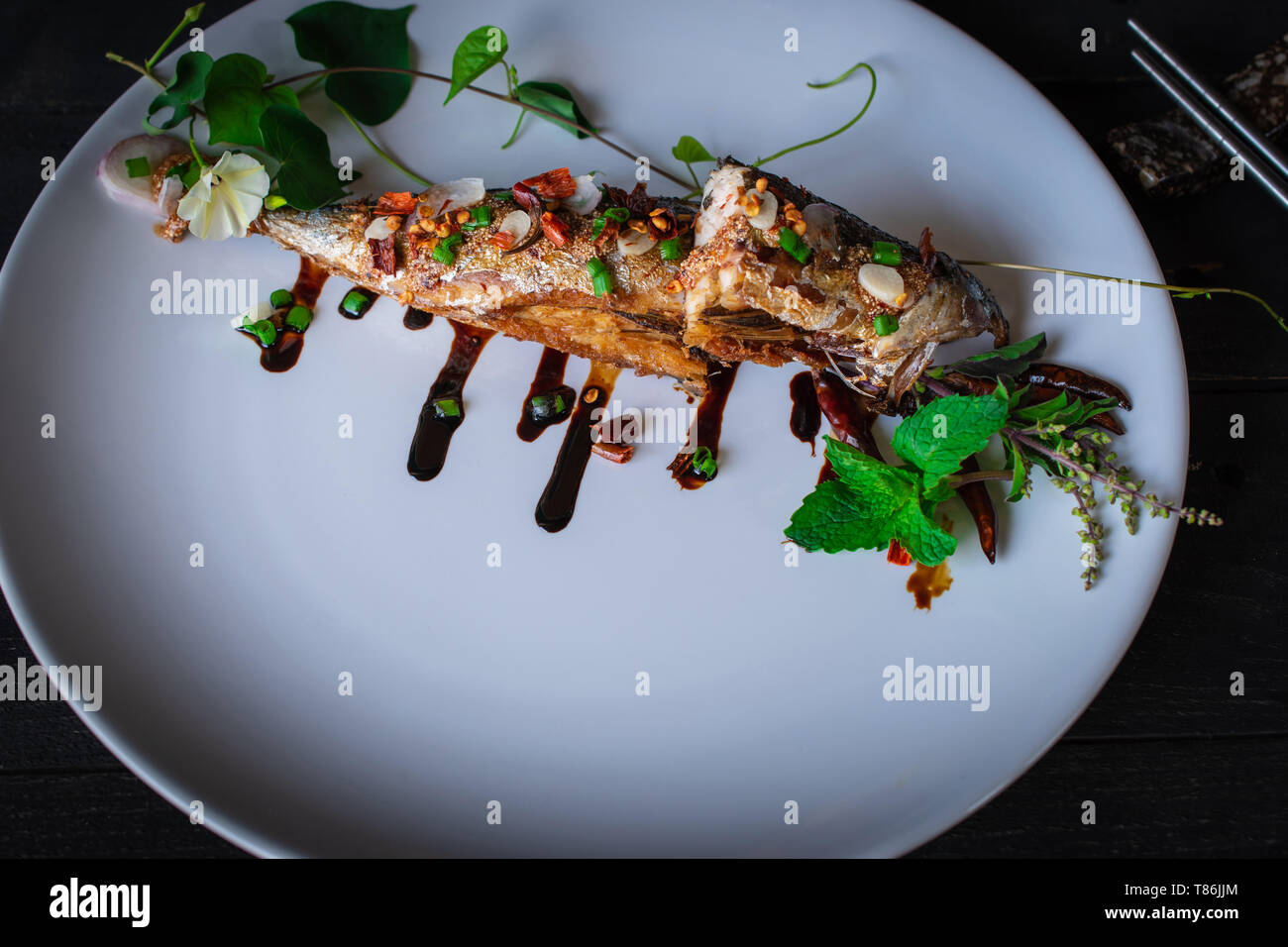 Fried Saba fish with Sauce on white plate and decoration by flower ...