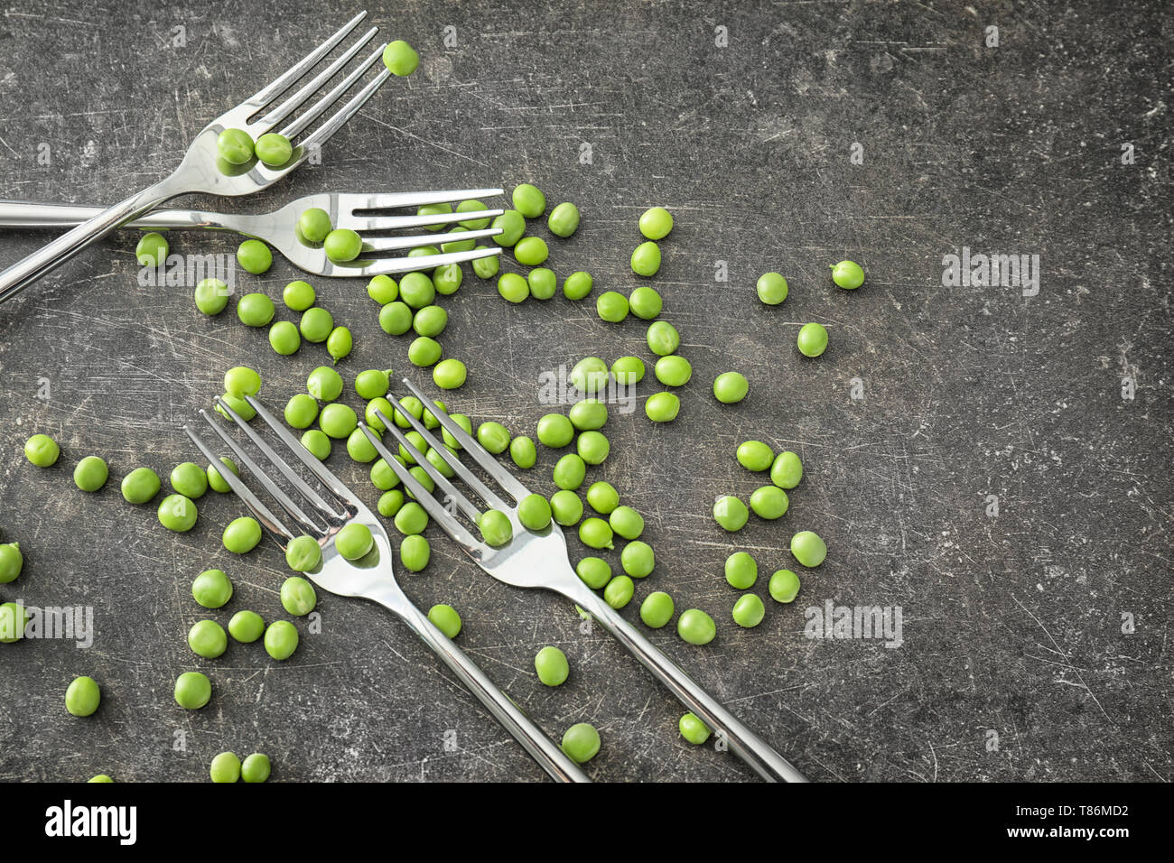 Fresh green peas and forks on grey background Stock Photo - Alamy