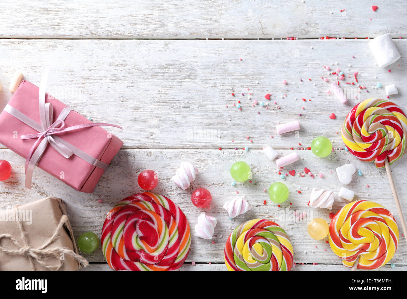 Composition with colorful candies and gift boxes on light wooden ...