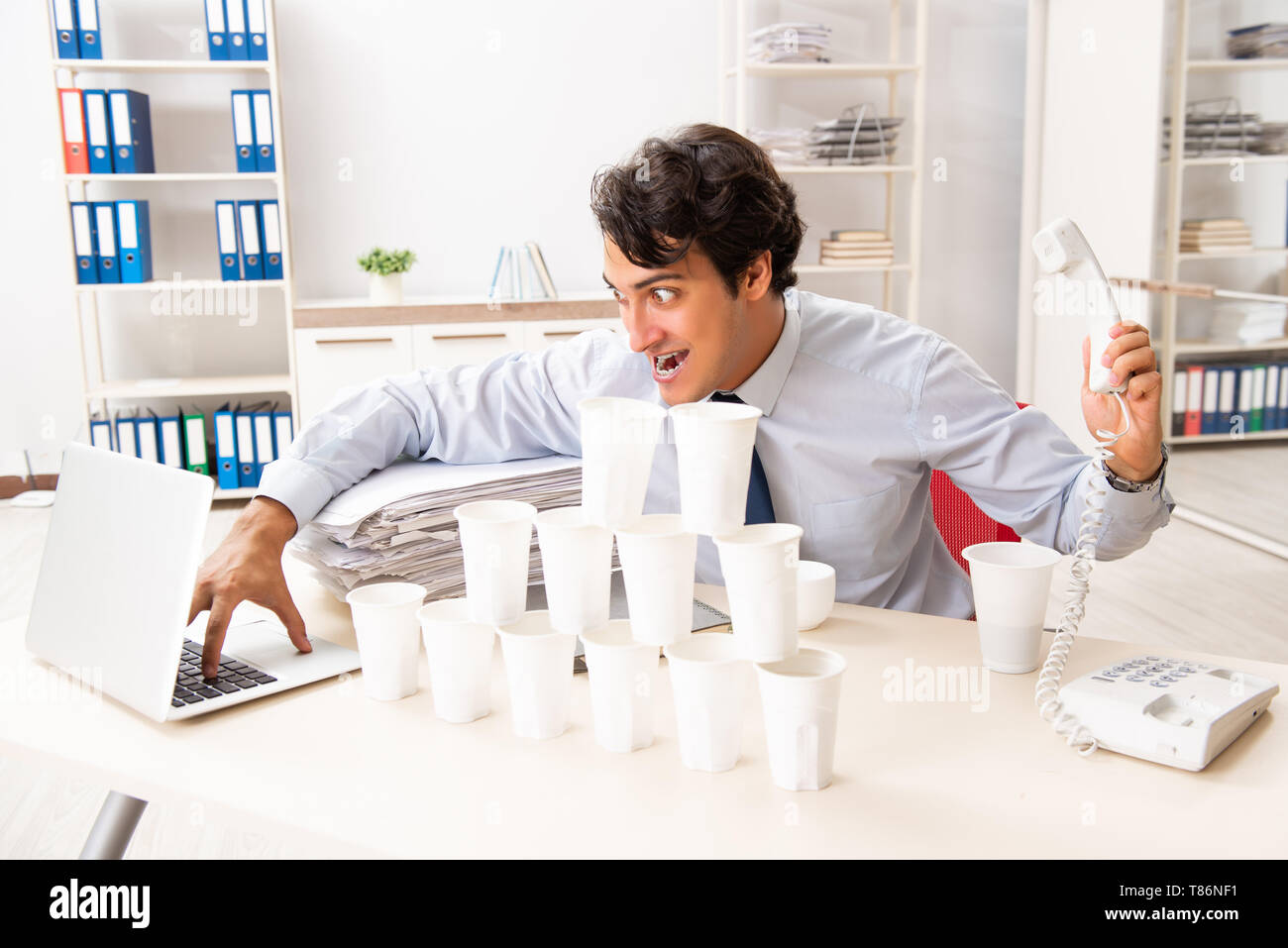 Young employee building pyramid from plastic cups Stock Photo - Alamy