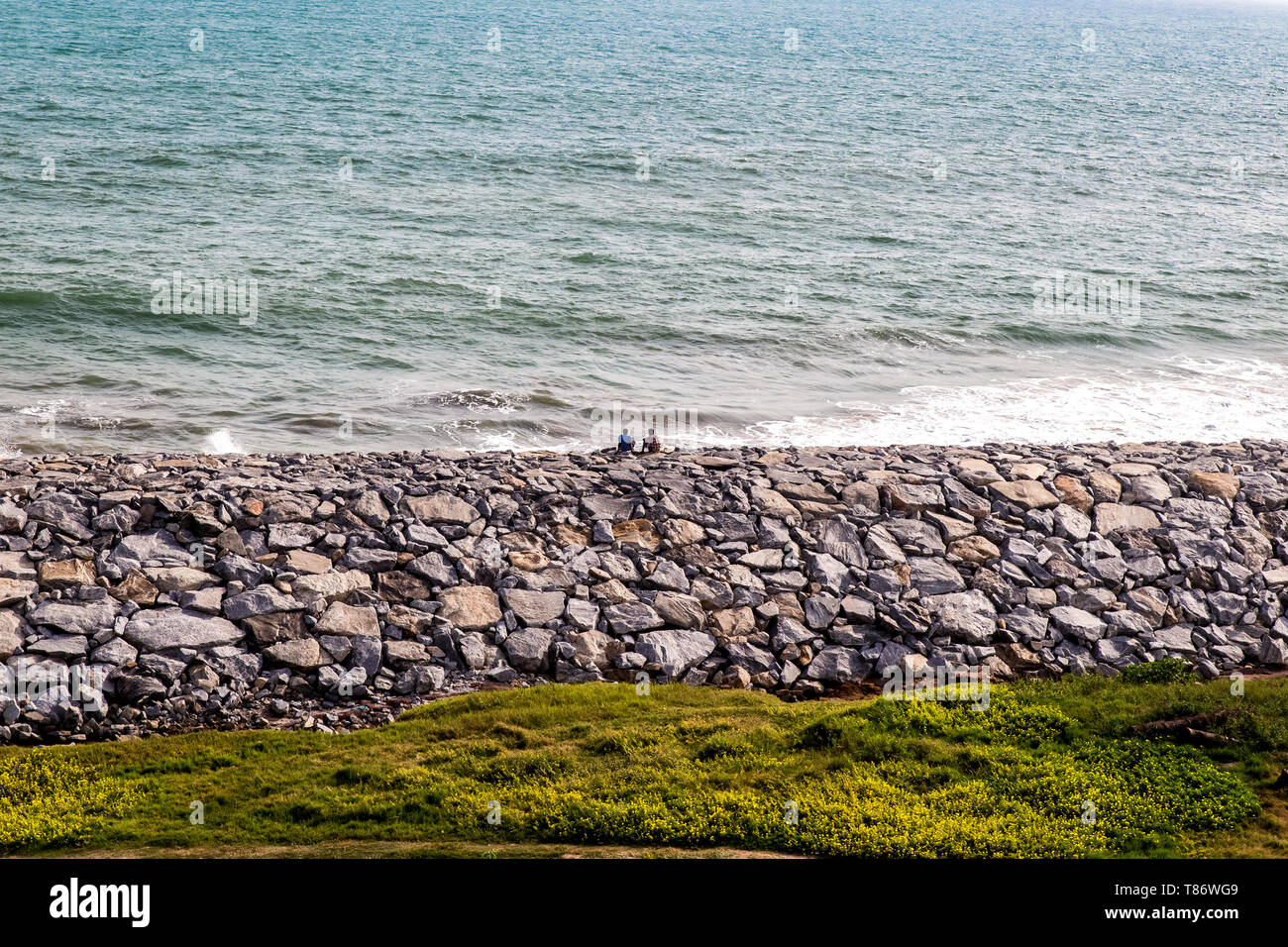 Two people sit on the bank of Cape Coast Beach Stock Photo - Alamy