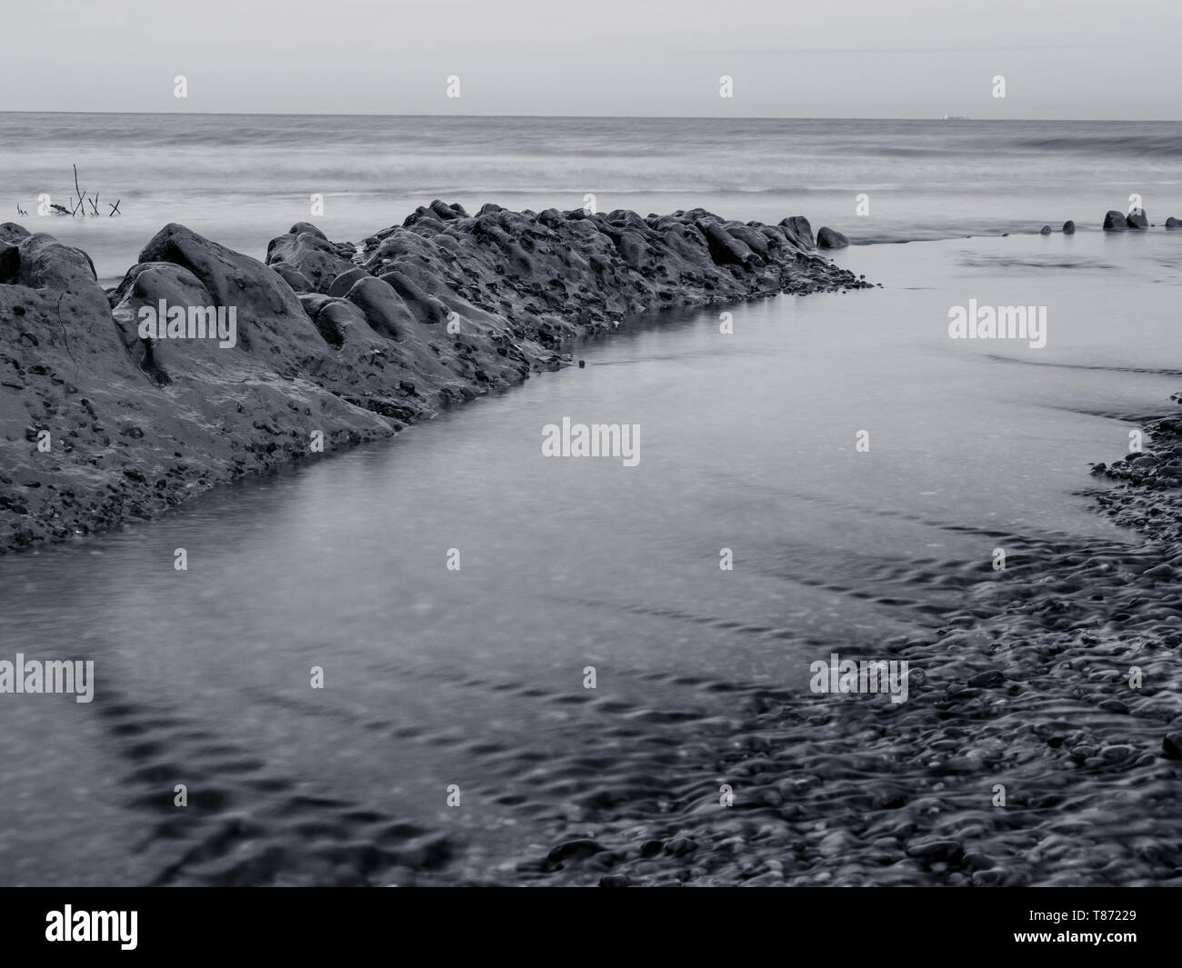 black and white long exposure of mud mounds by shingle street sea front ...