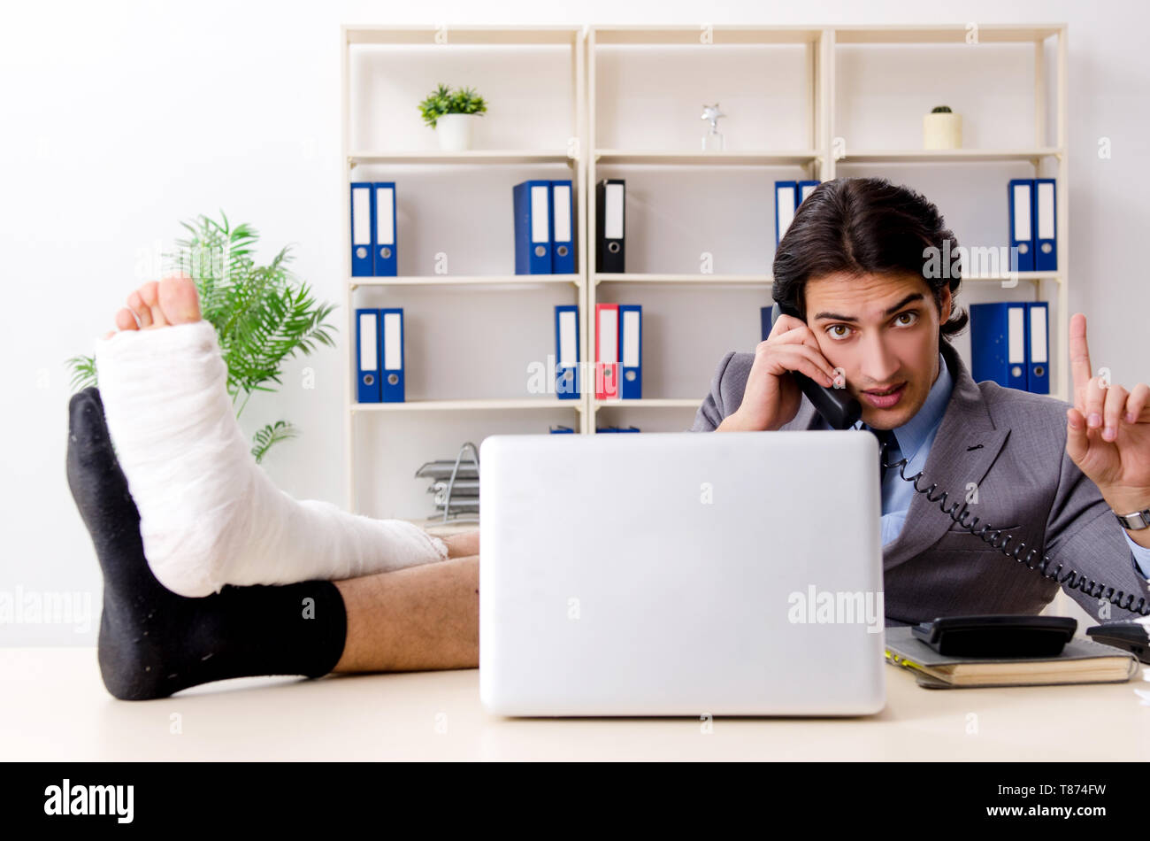 Leg injured employee working in the office Stock Photo - Alamy