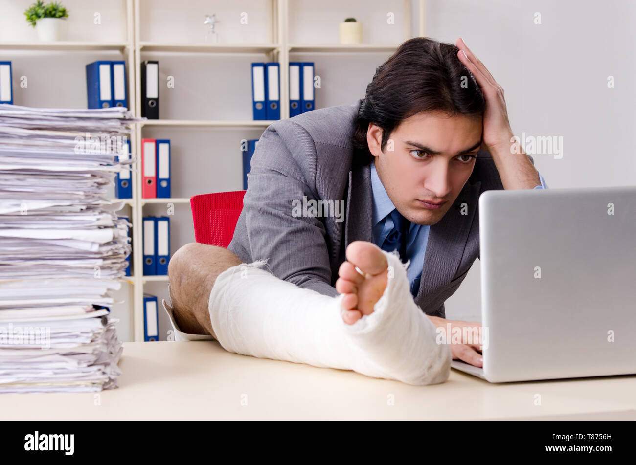 Leg injured employee working in the office Stock Photo - Alamy