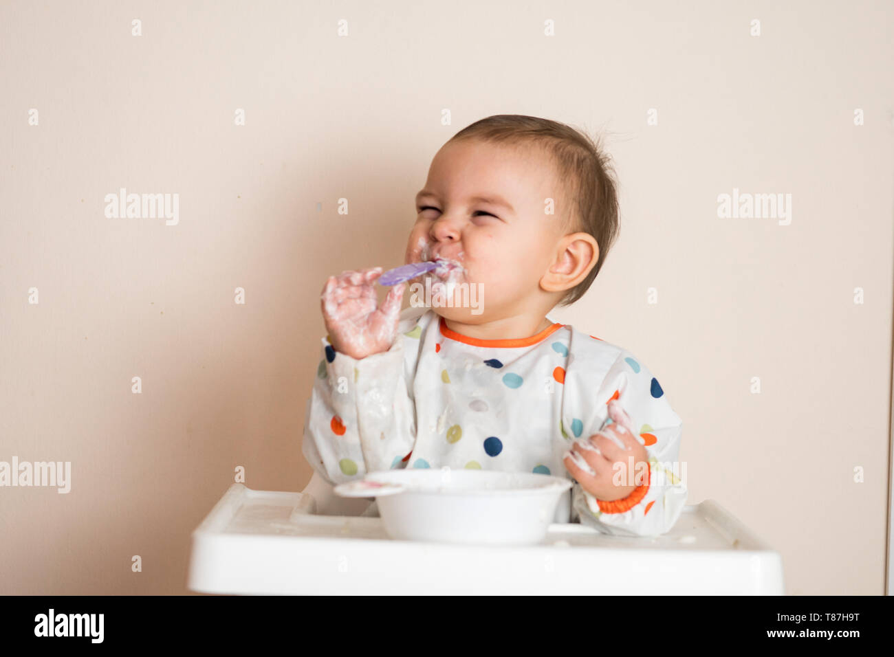 A Little baby eating her dinner and making a mess with yogurt and ...