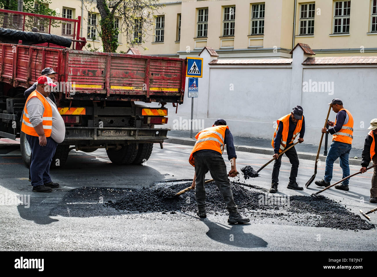Sibiu City, Romania - 9 May 2019. Workers repair broken asphalt road in ...