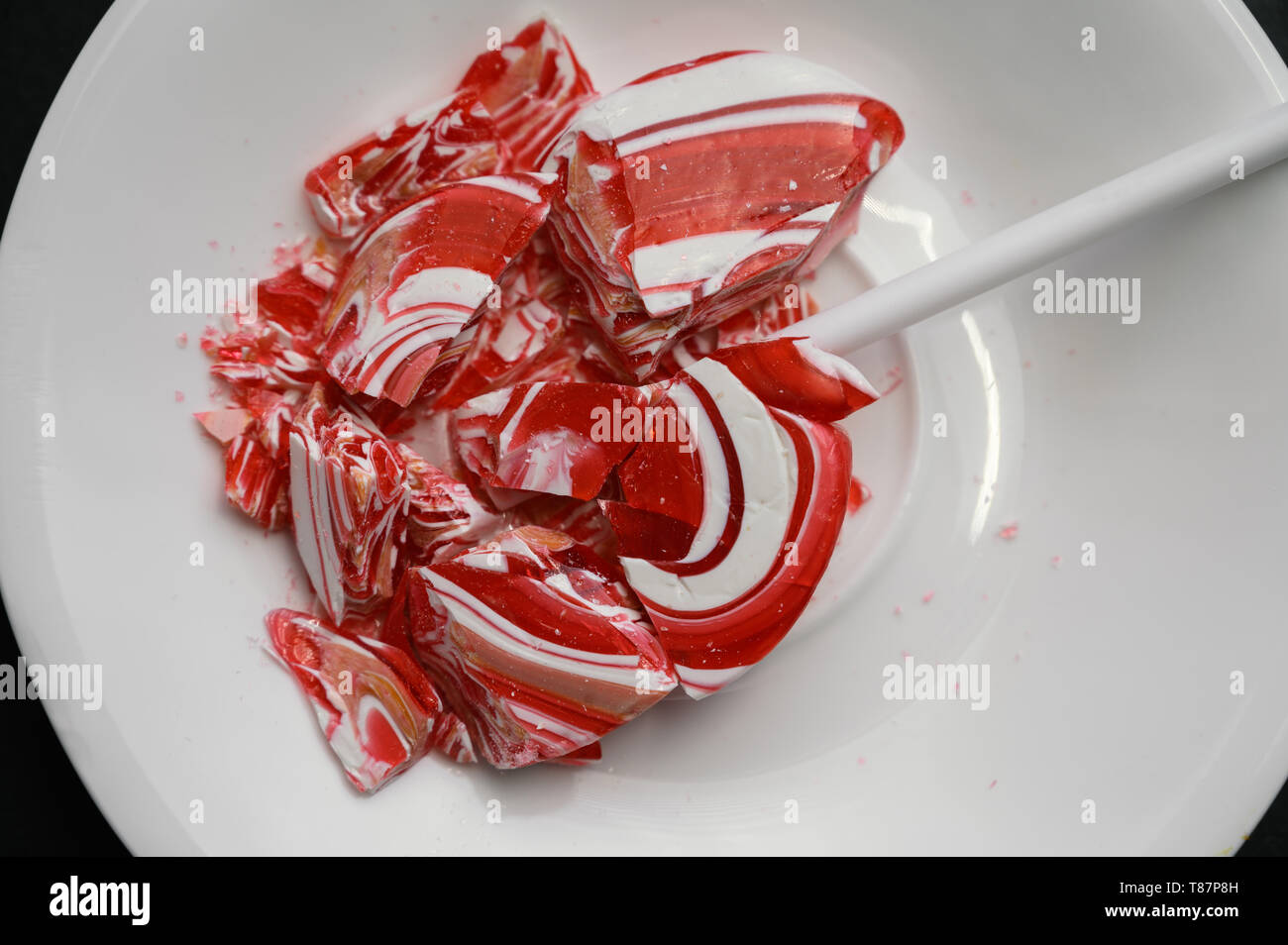 Broken lollipop in dish on a dark background Stock Photo - Alamy
