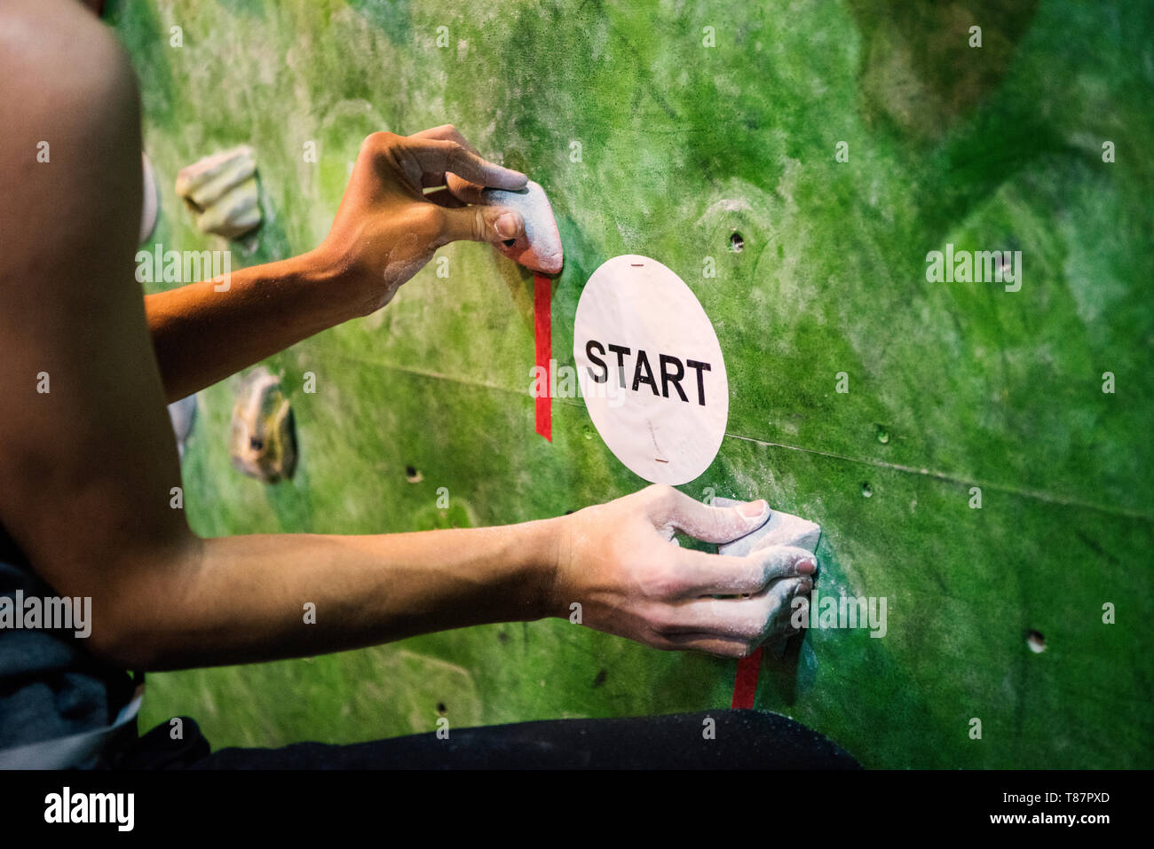 A man holds rock climbing wall stones in start point Stock Photo - Alamy