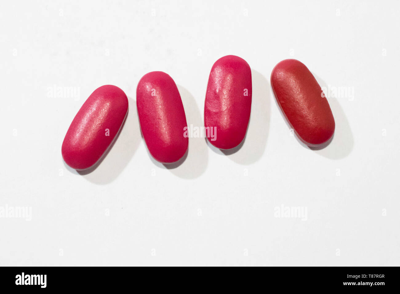 Four red pills shaped like a bean isolated on a white background Stock ...