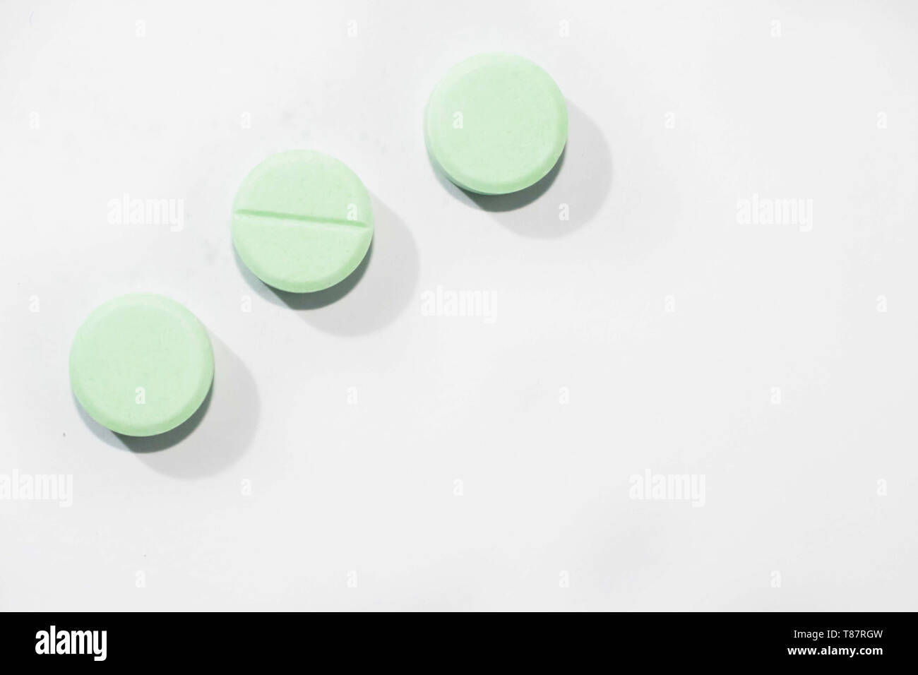 Three round green pills arranged diagonally on a white background Stock ...