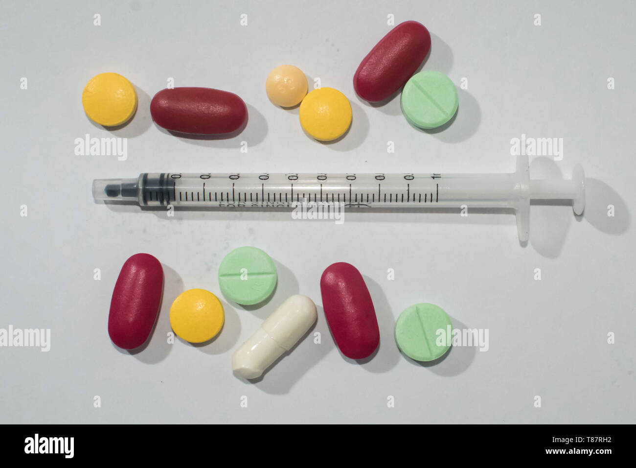 Variety of pills with a single injection at the center, medical concept ...