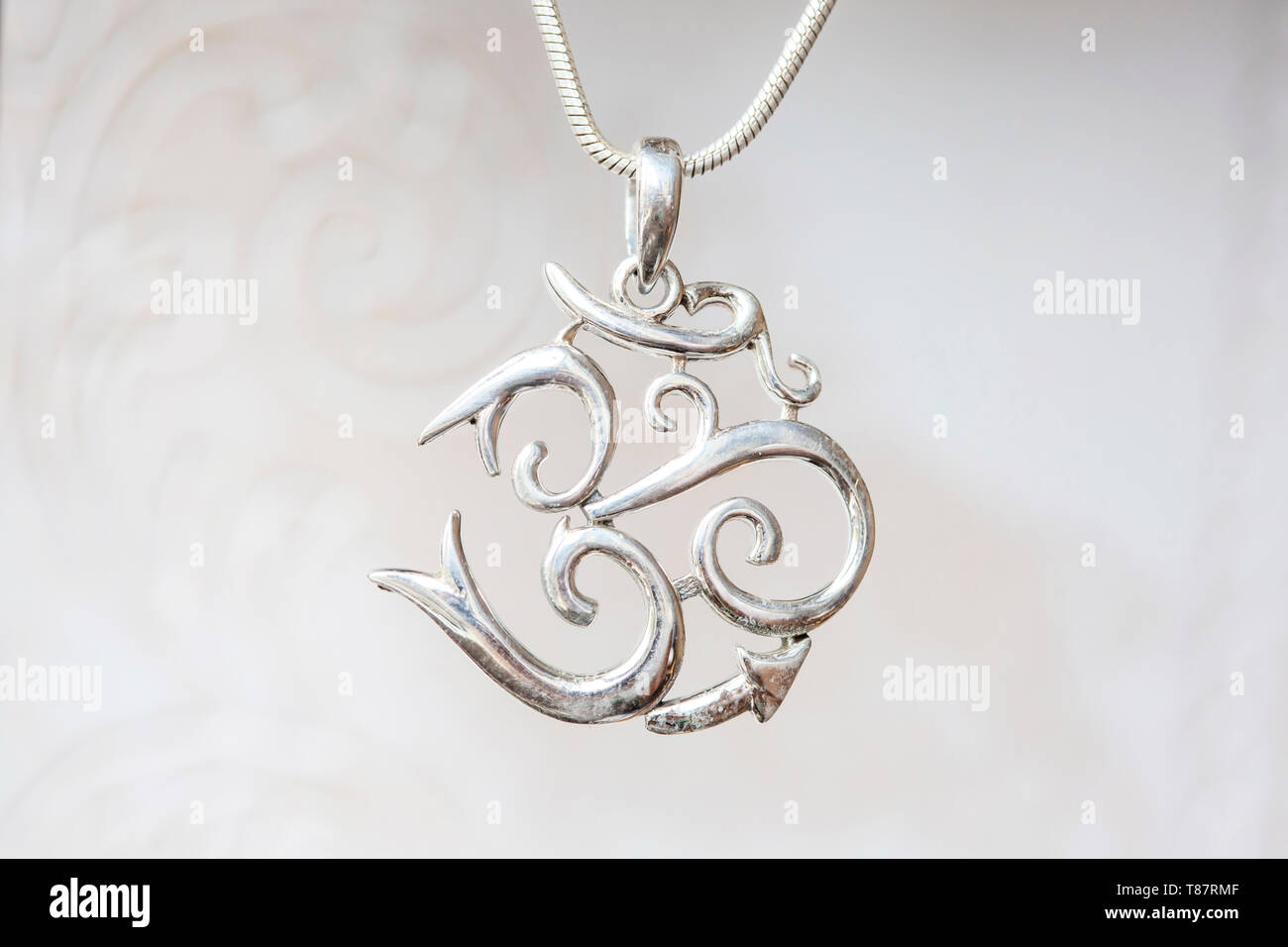 Silver Om pendant on natural white background Stock Photo - Alamy