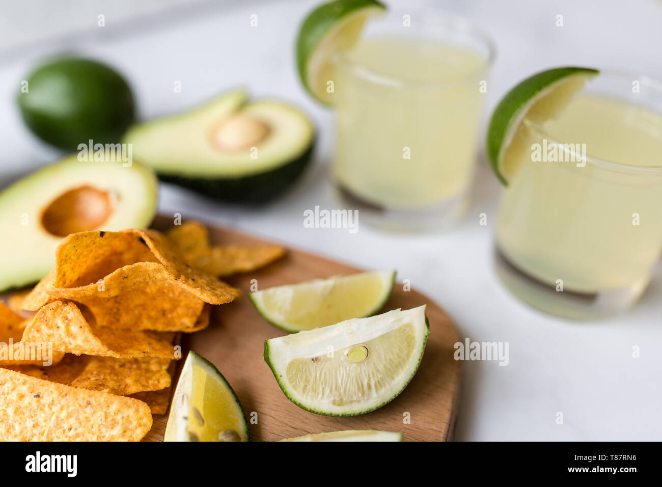 High angle view of two margarita cocktails surrounded by nachos, chips ...