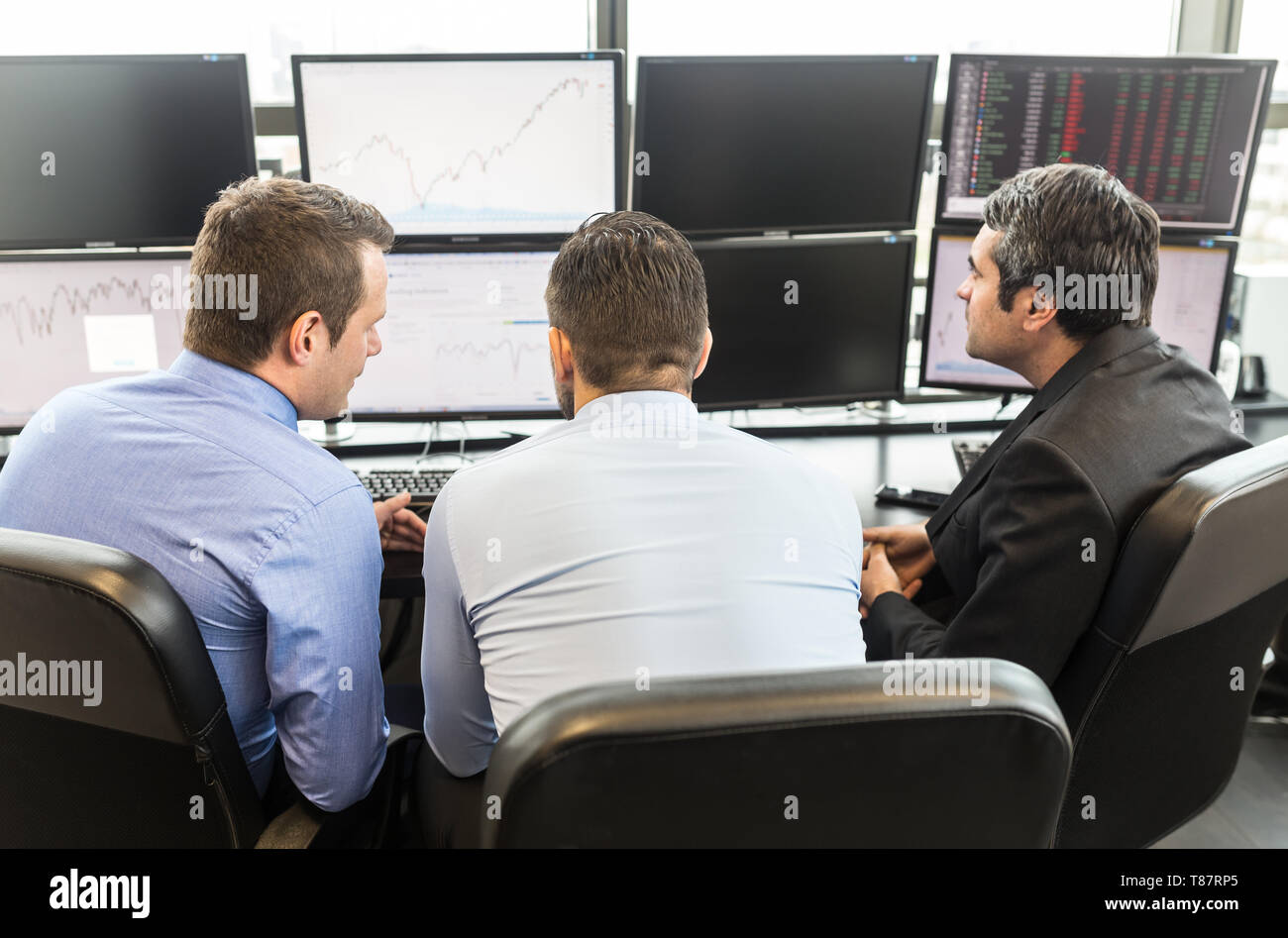 Business team brainstorming while checking data at computer screens ...