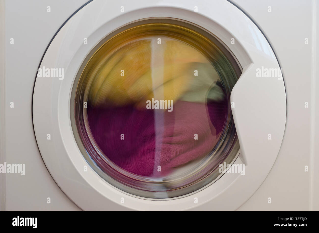 Washing machine door with rotating garments inside Stock Photo - Alamy