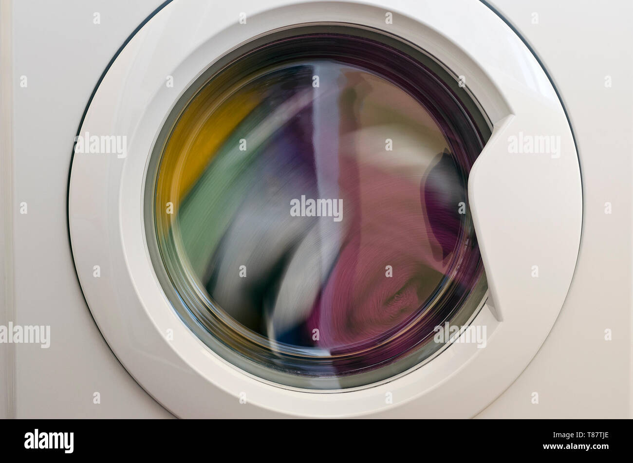 Washing machine door with rotating garments inside Stock Photo - Alamy