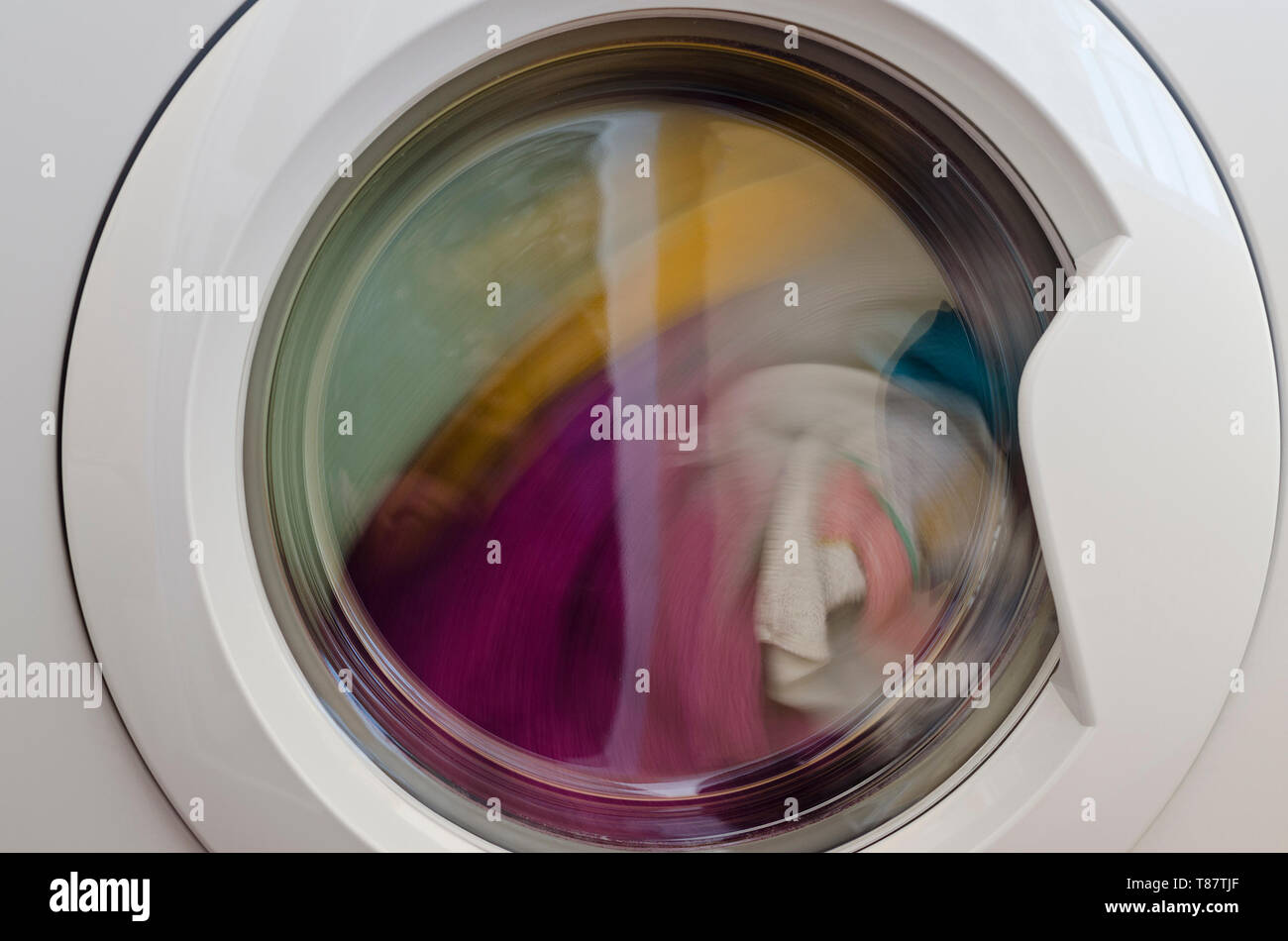 Washing machine door with rotating garments inside Stock Photo - Alamy