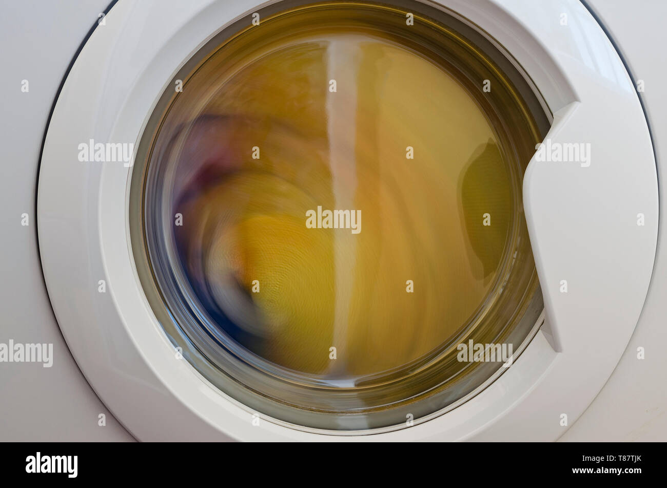 Washing machine door with rotating garments inside Stock Photo - Alamy