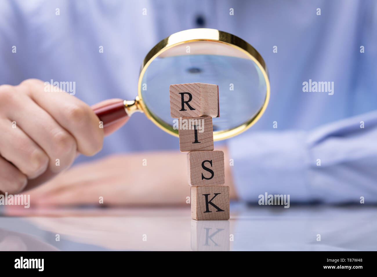 Close-up Of Wooden Blocks With Risk Word In Front Of Businessperson's ...