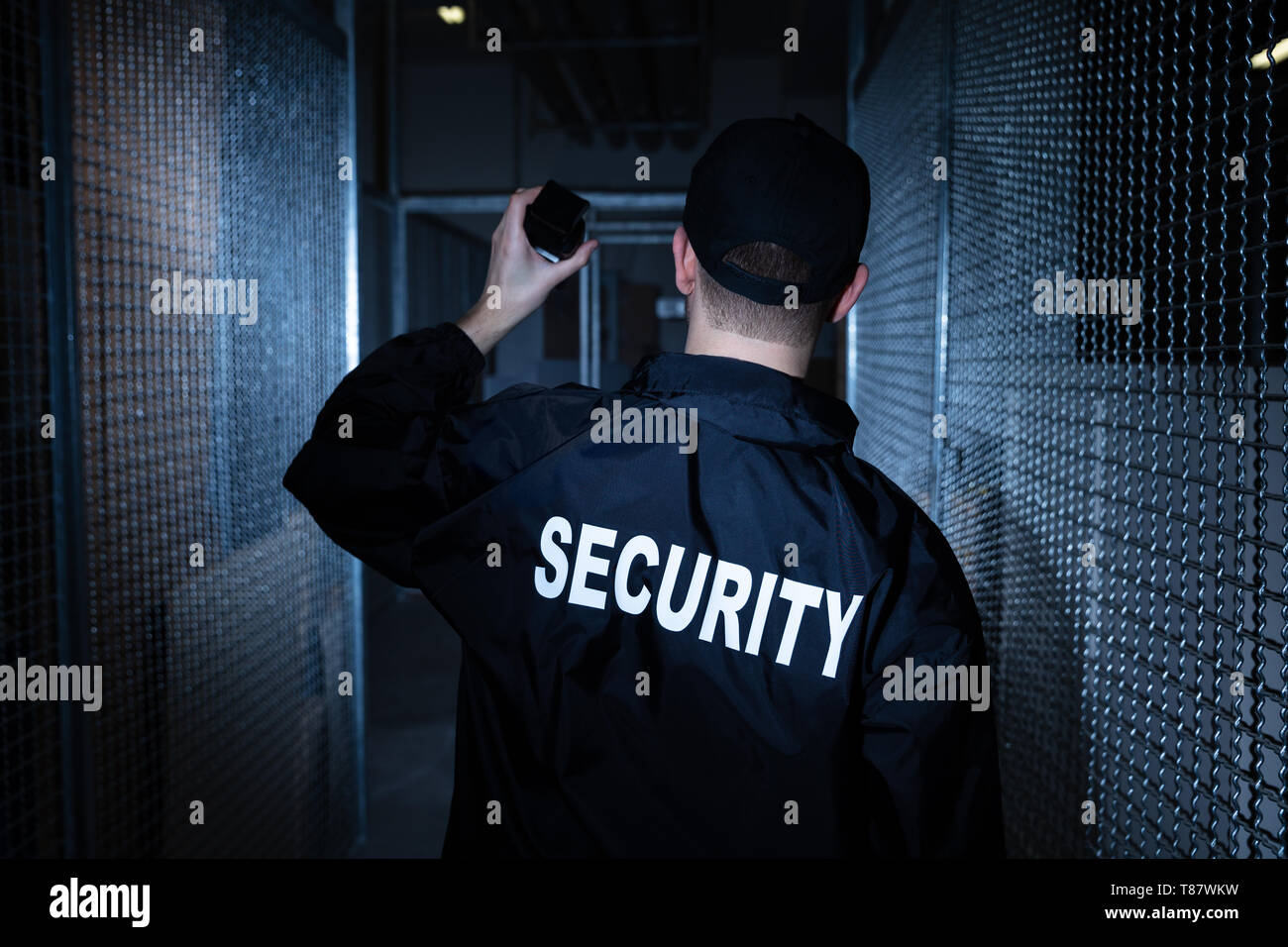 Rear View Of A Security Guard Standing In The Warehouse Holding ...