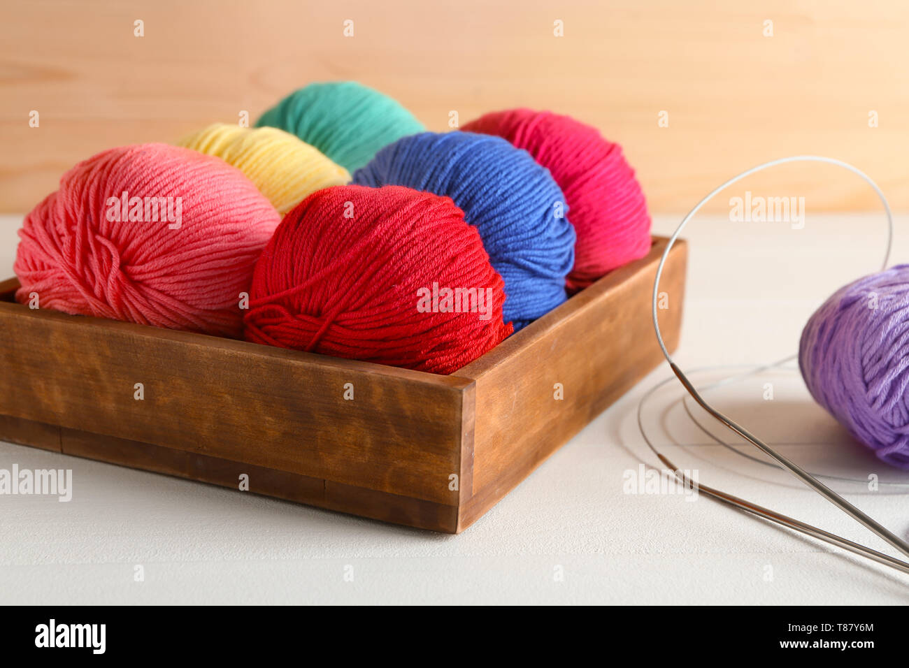 Box with balls of knitting yarn and needles on light table Stock Photo ...