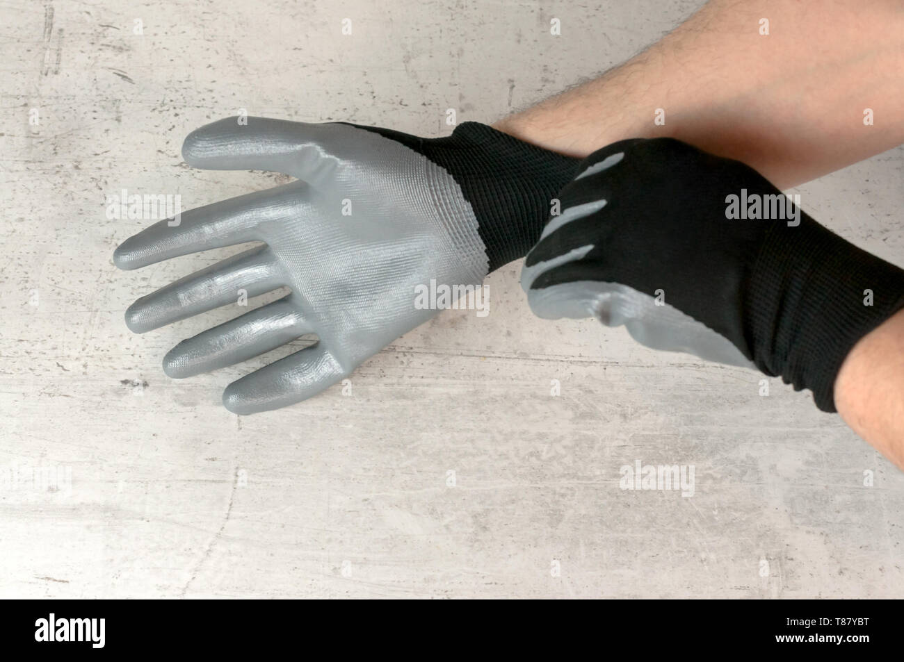 A man puts on a glove on his hand for repairs. Hand on light concrete ...