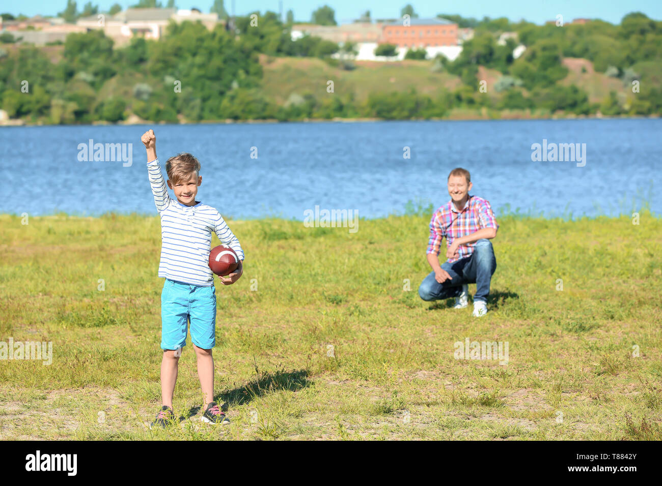 Happy father and son playing rugby near river Stock Photo - Alamy