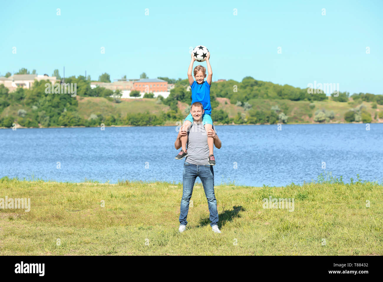 Happy father and son with soccer ball near river Stock Photo - Alamy