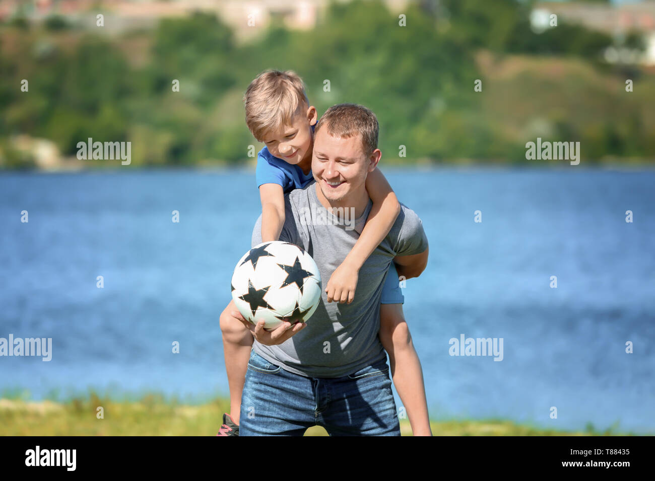 Happy father and son with soccer ball near river Stock Photo - Alamy