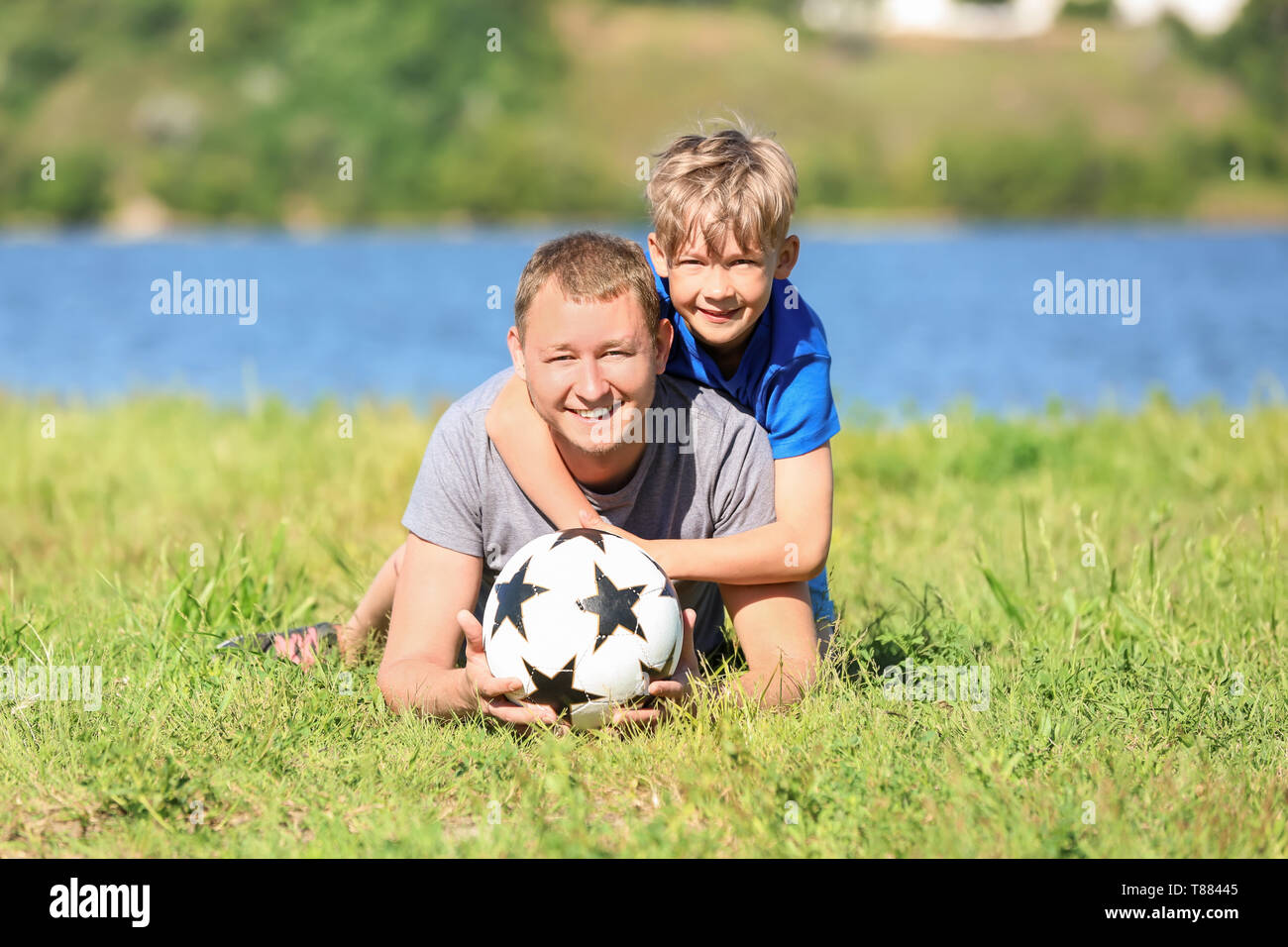 Happy father and son with soccer ball near river Stock Photo - Alamy