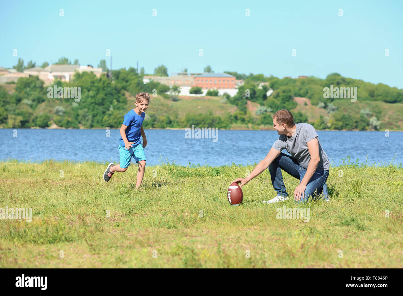 Happy father and son playing rugby near river Stock Photo - Alamy