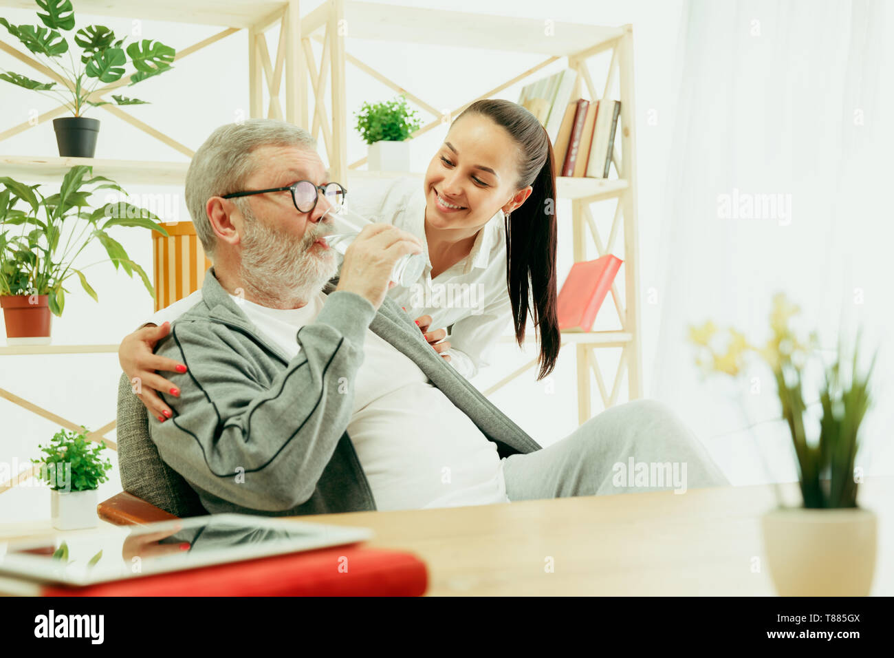 A daughter or granddaughter spends time with the grandfather or senior ...