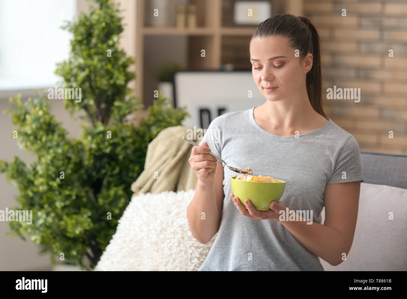 Beautiful young woman eating tasty oatmeal at home Stock Photo - Alamy