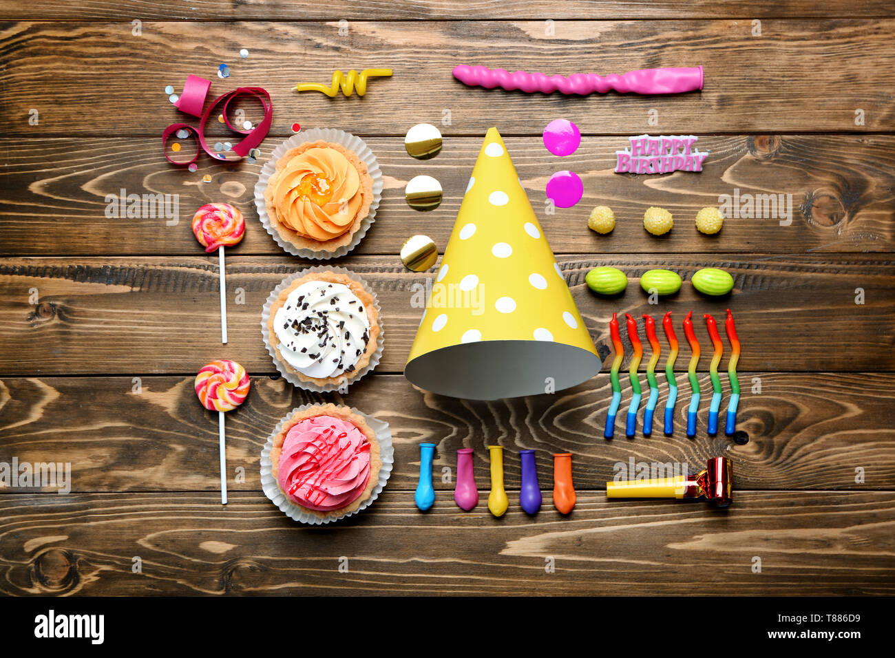 Birthday composition with party items and sweets on wooden background ...