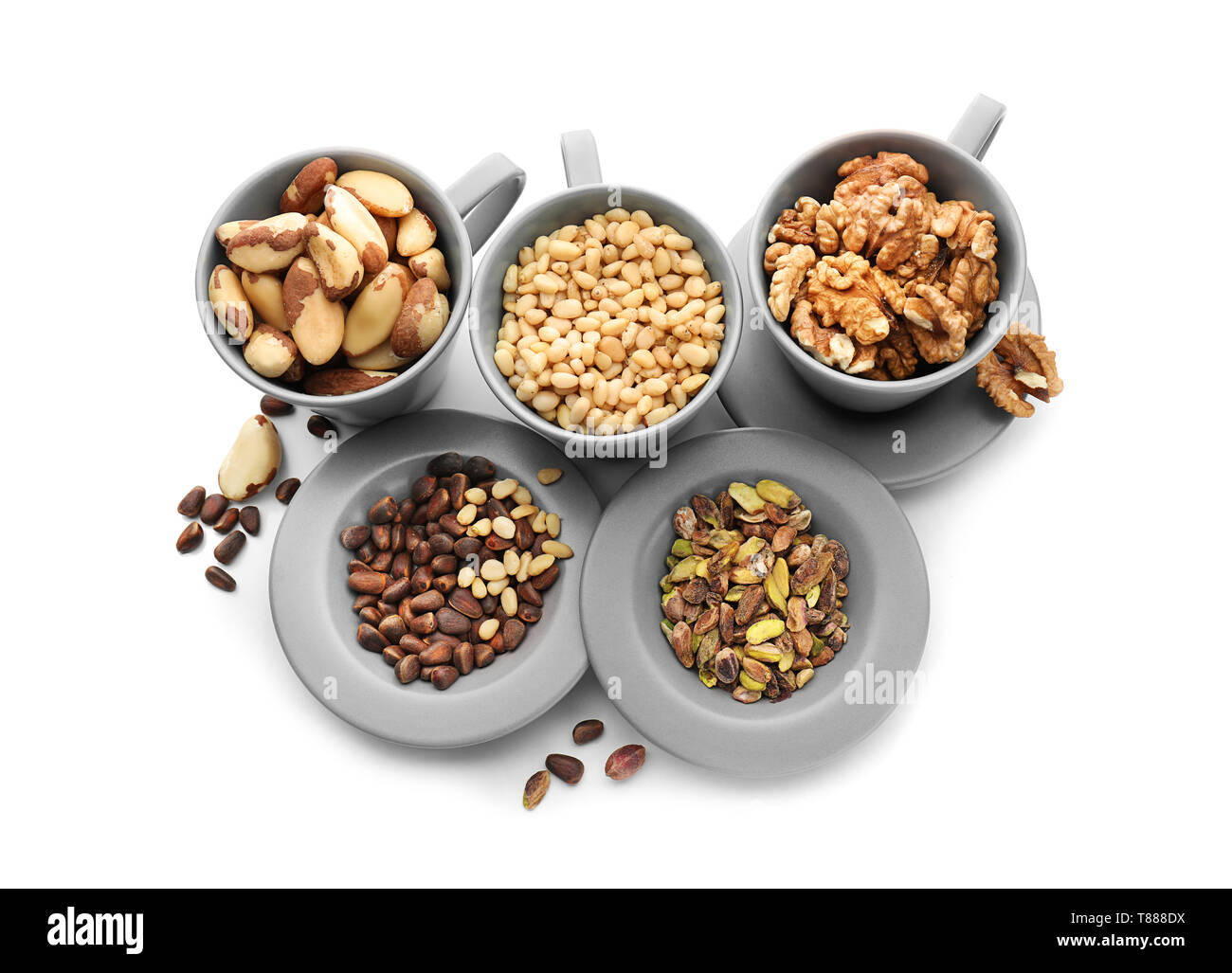 Cups and plates with different nuts on white background Stock Photo - Alamy