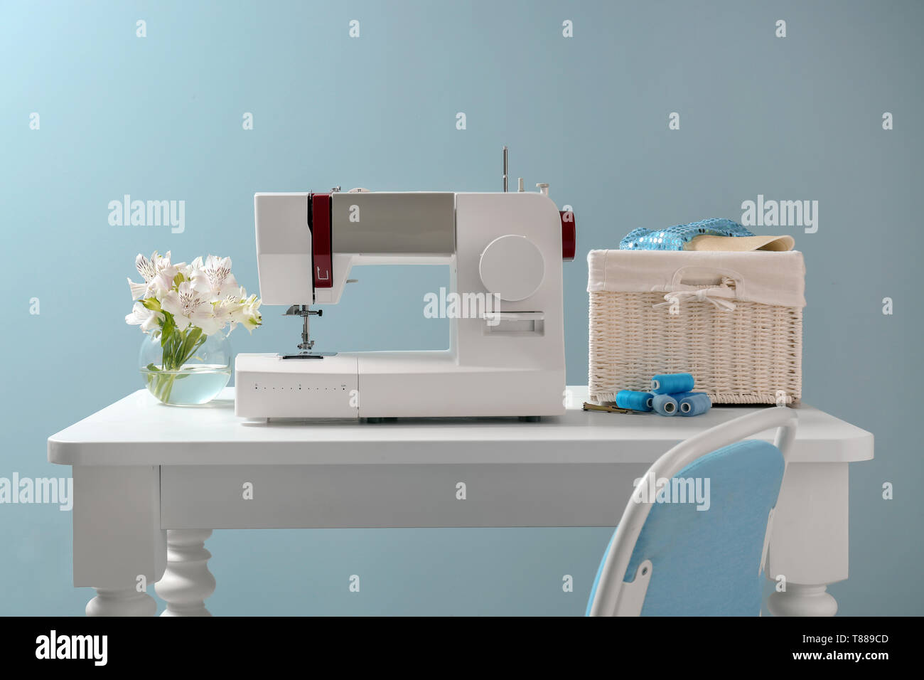 Table with modern sewing machine on color background Stock Photo - Alamy