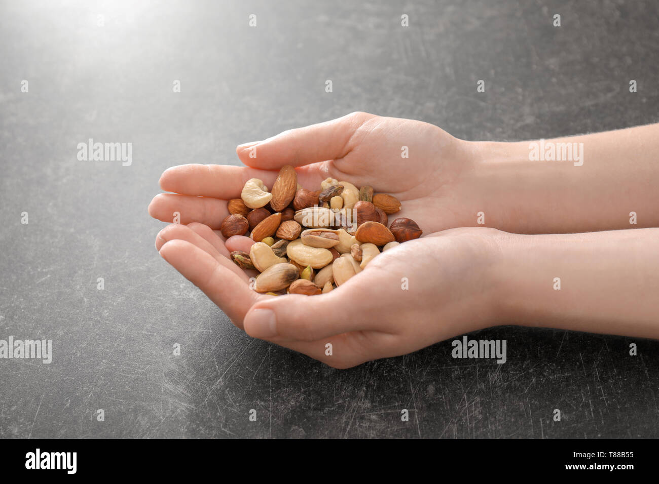 Woman holding different nuts on grey background Stock Photo - Alamy