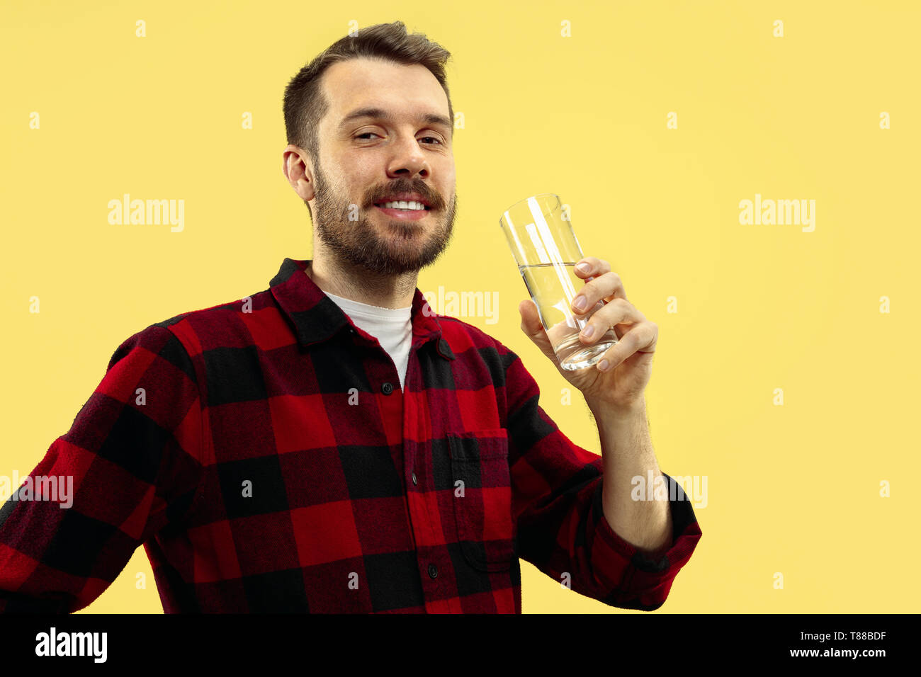 Half-length close up portrait of young man in shirt on yellow ...