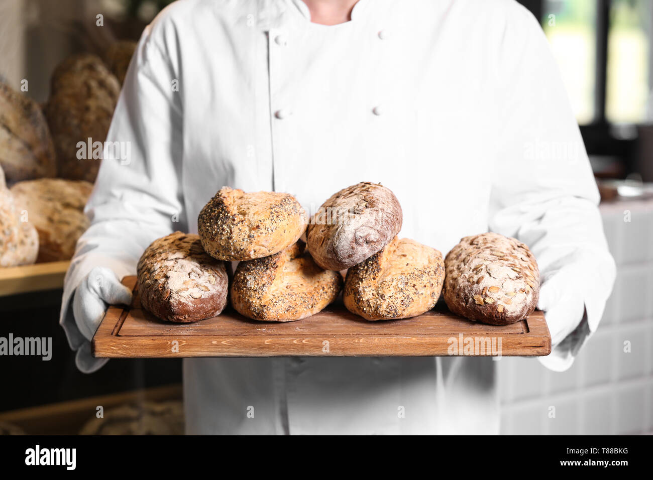 Man holding board with assortment of fresh bread in bakery Stock Photo ...