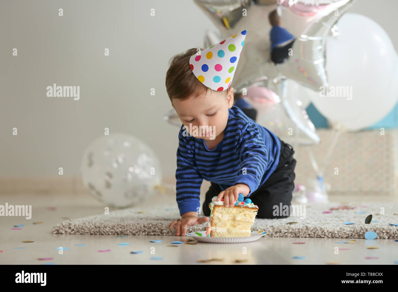 Cute little boy with piece of birthday cake in room Stock Photo - Alamy