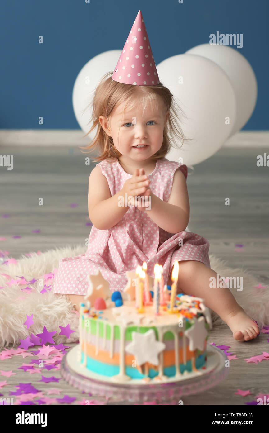Cute little girl with birthday cake sitting on fluffy rug indoors Stock ...