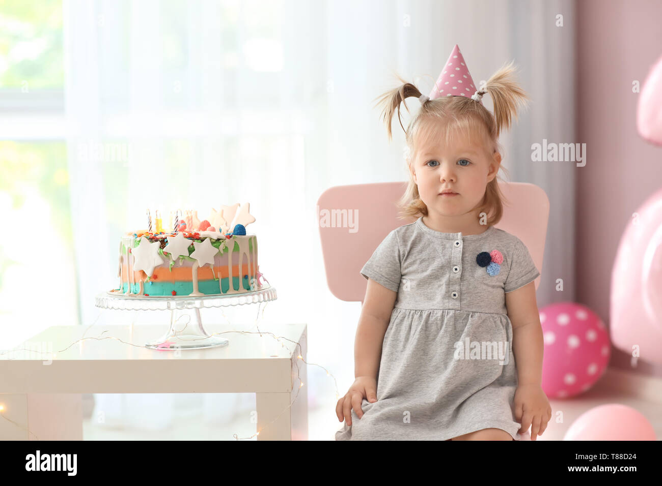 Cute little girl with delicious cake sitting on chair in room Stock ...